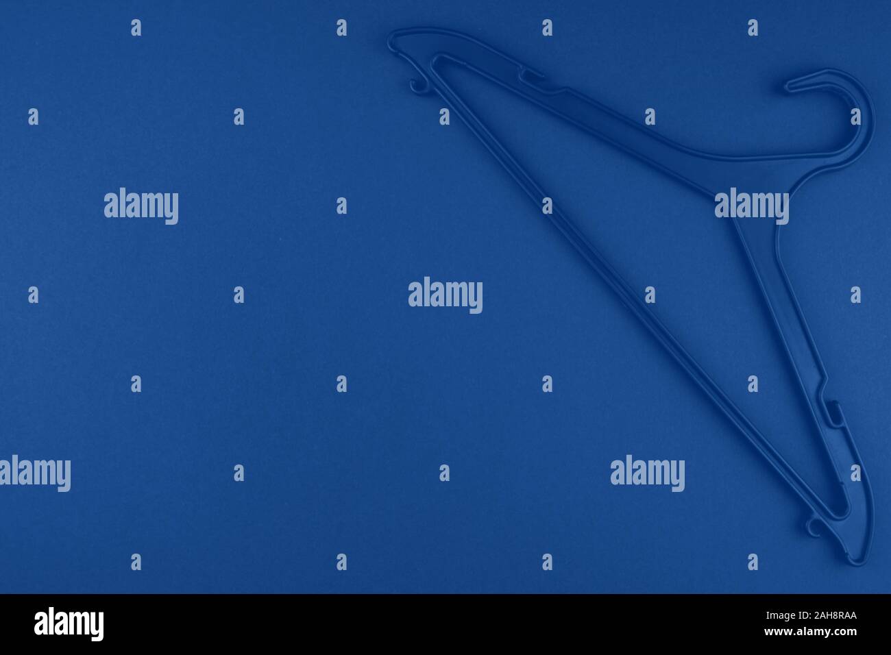 Creative blue plastic hanger on trendy classic blue color backdrop ...