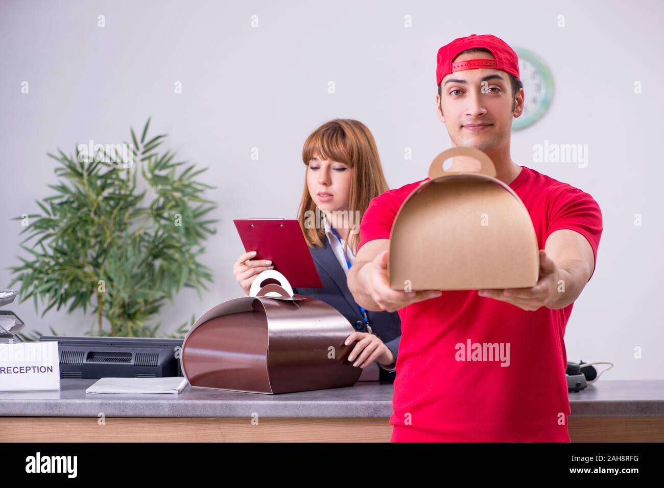 The young male courier delivering cake to hotel's reception Stock Photo ...
