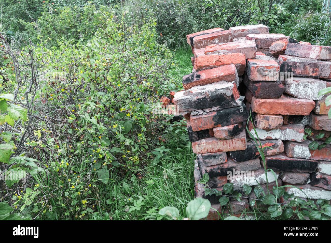Pile of stacked rows of old, cracked, burnt bricks in an abandoned ...
