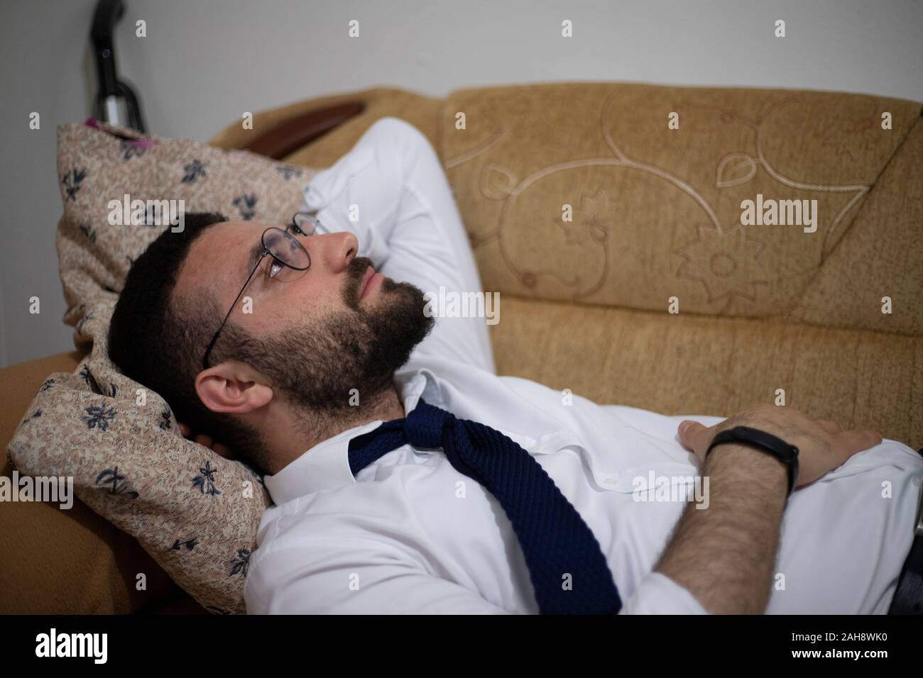 man after work thinking laying down on the couch Stock Photo - Alamy