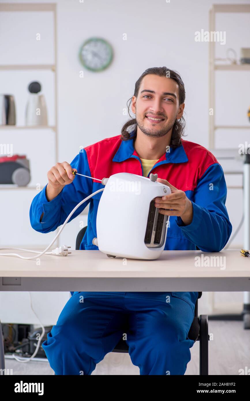 The young male contractor repairing toaster at workshop Stock Photo - Alamy