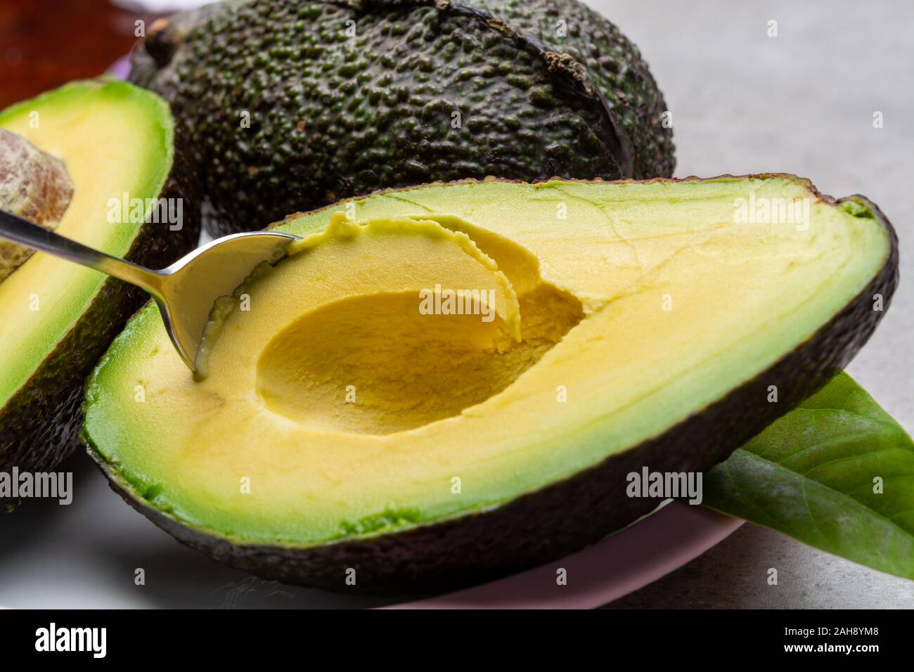 Eating of fresh ripe green organic hass avocado fruit with spoon close ...