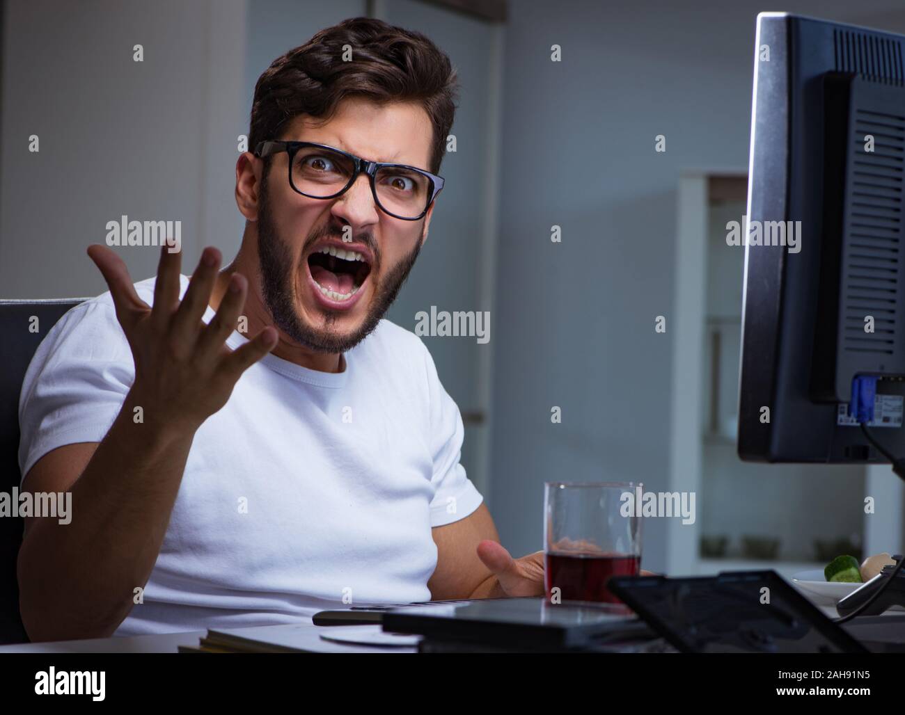 Young man staying late in office to do overtime work Stock Photo - Alamy