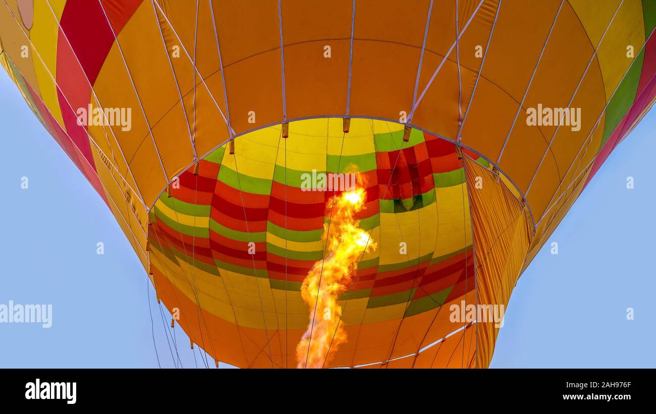 A close-up view of a flame heating the air inside a colorful hot air ...