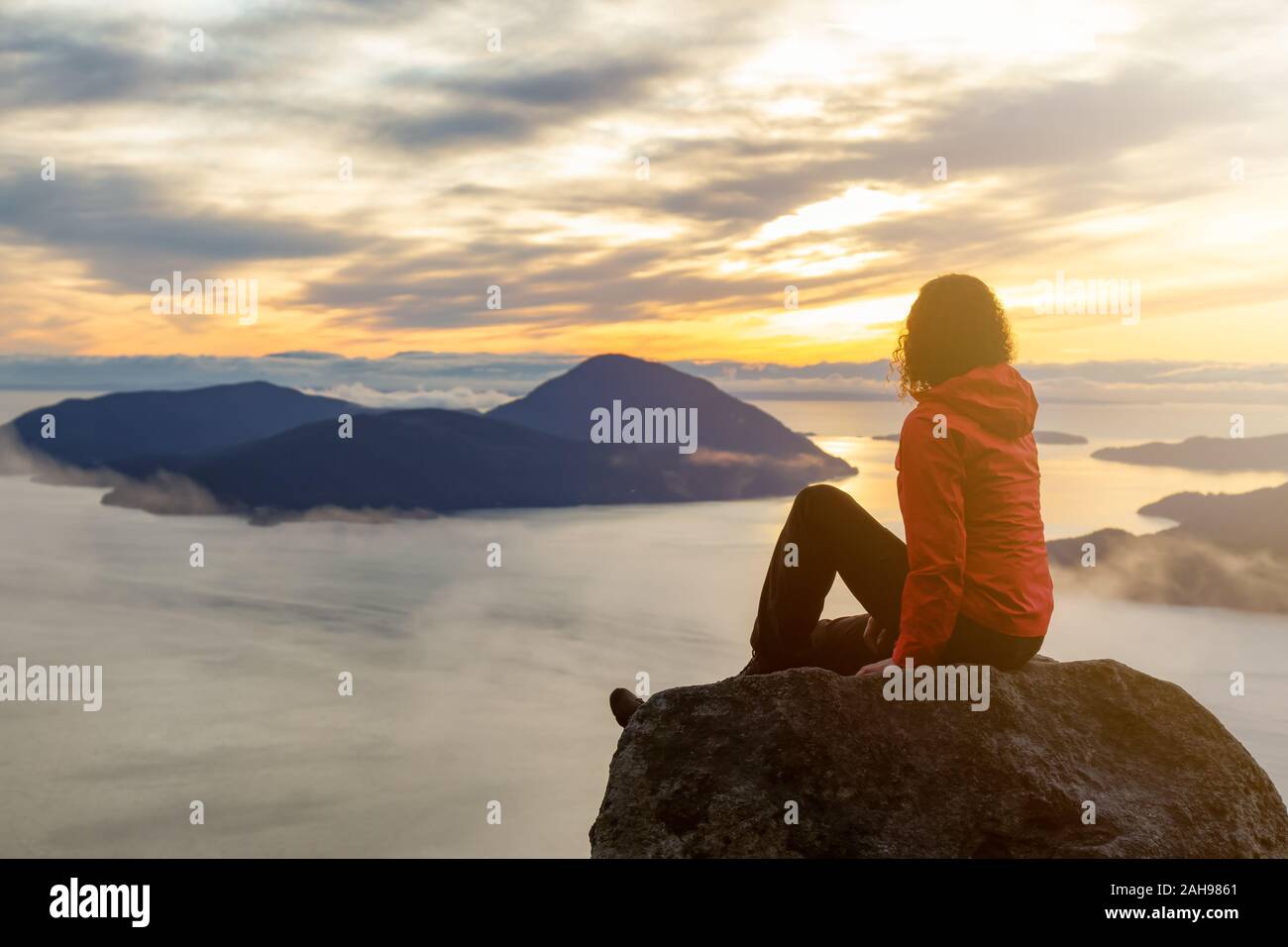 Adventurous Girl on top of a Mountain during Sunset Stock Photo - Alamy