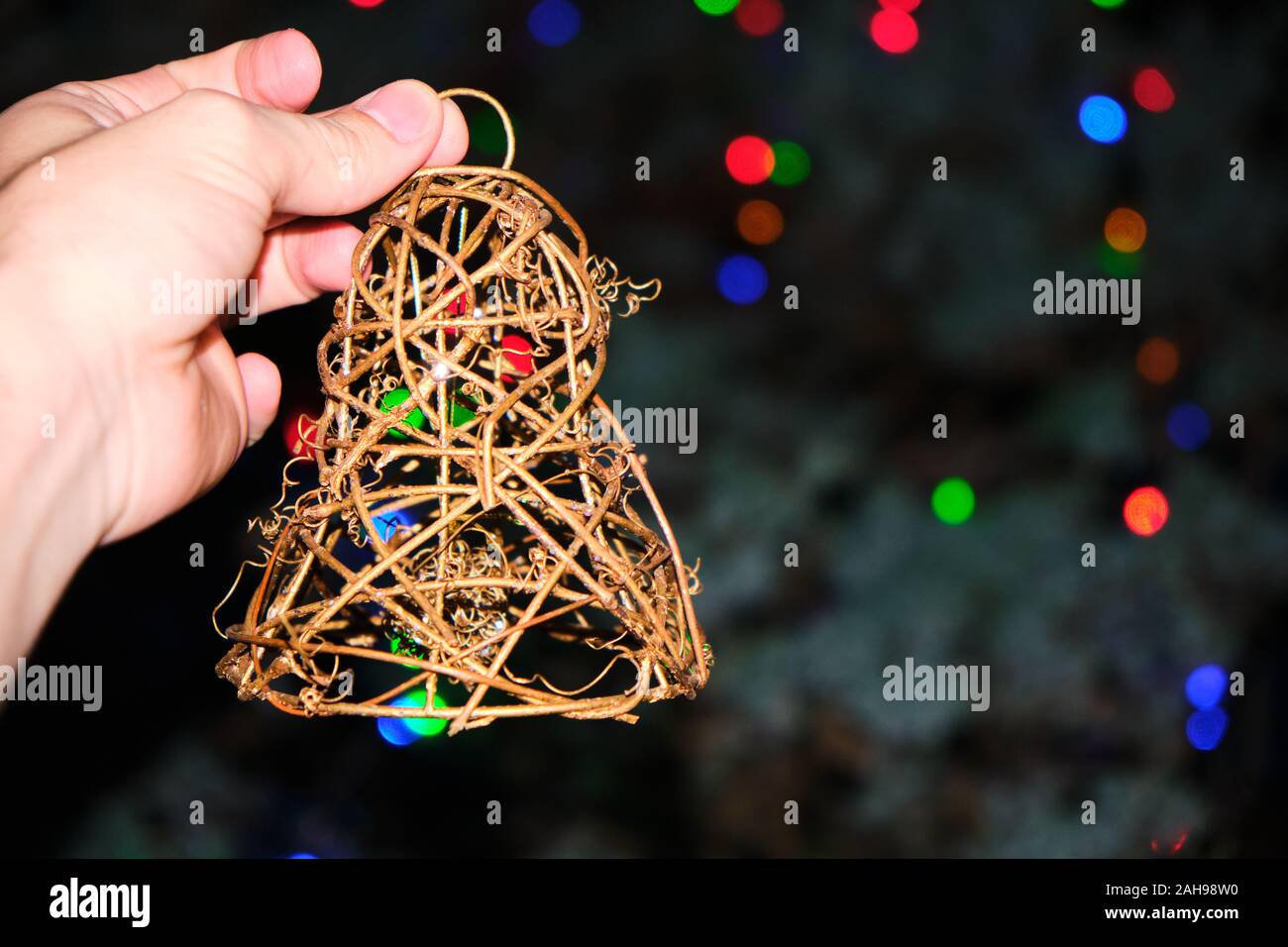 front photo of a handmade bell made of wicker, held by a hand of a ...