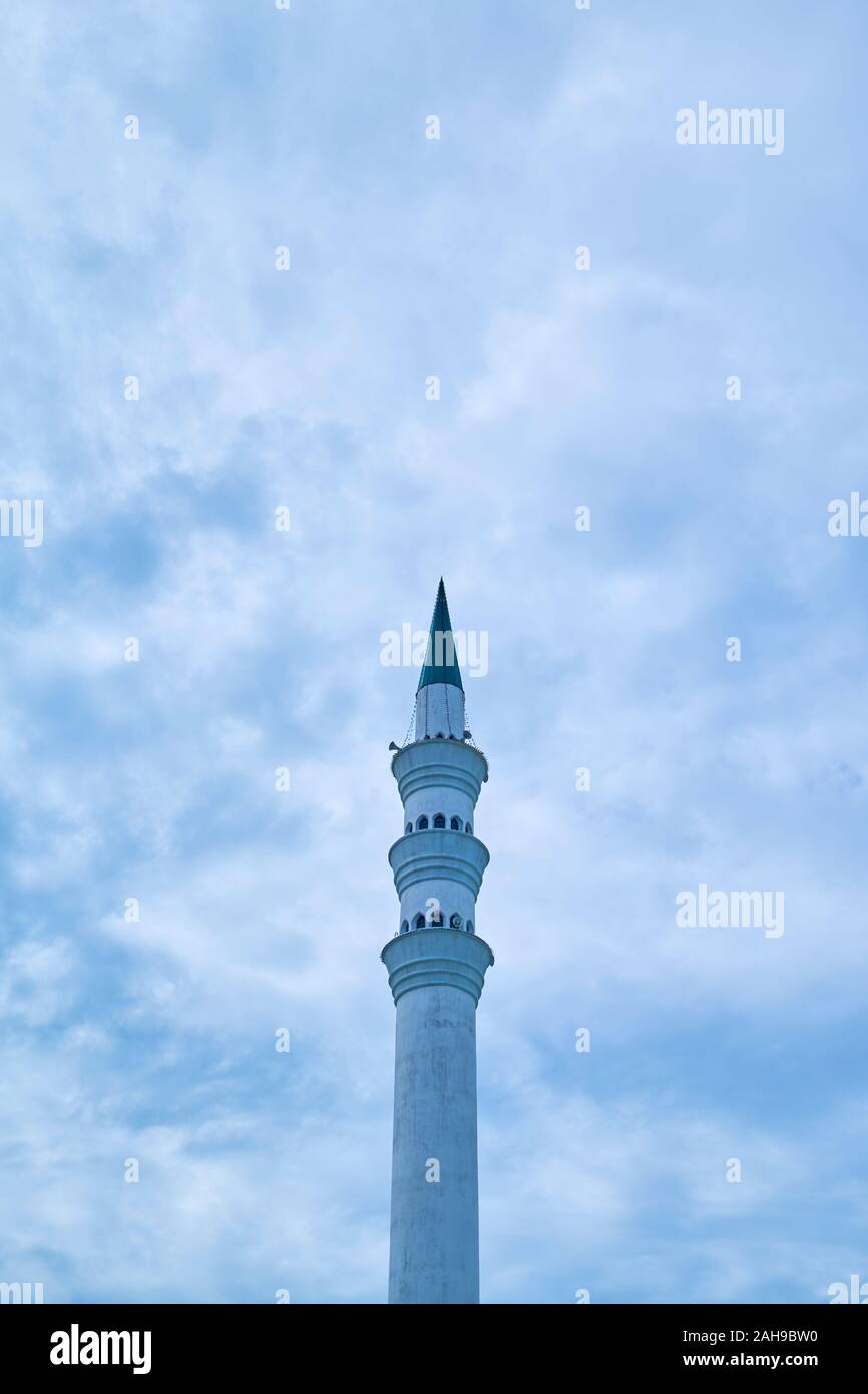 The lone, white minaret of the Al-Kauthar mosque stands against a blue ...