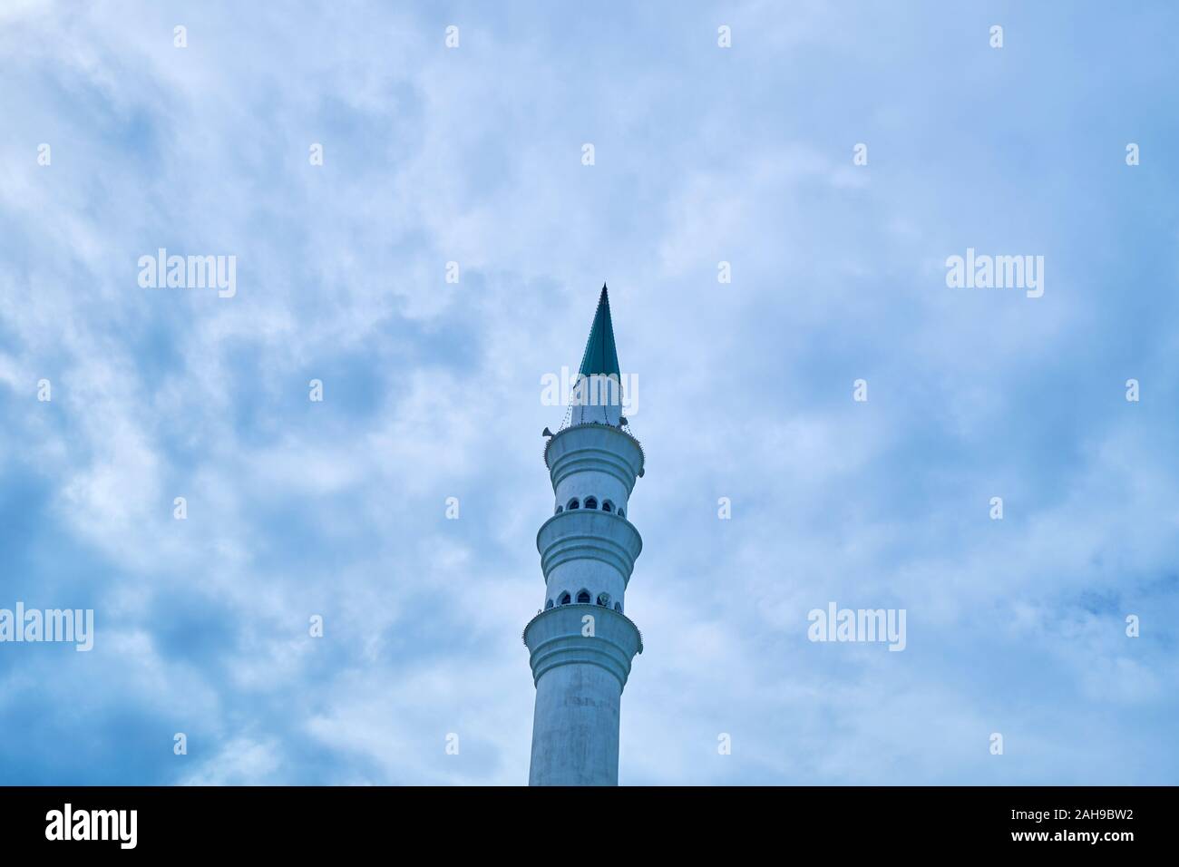 The lone, white minaret of the Al-Kauthar mosque stands against a blue ...