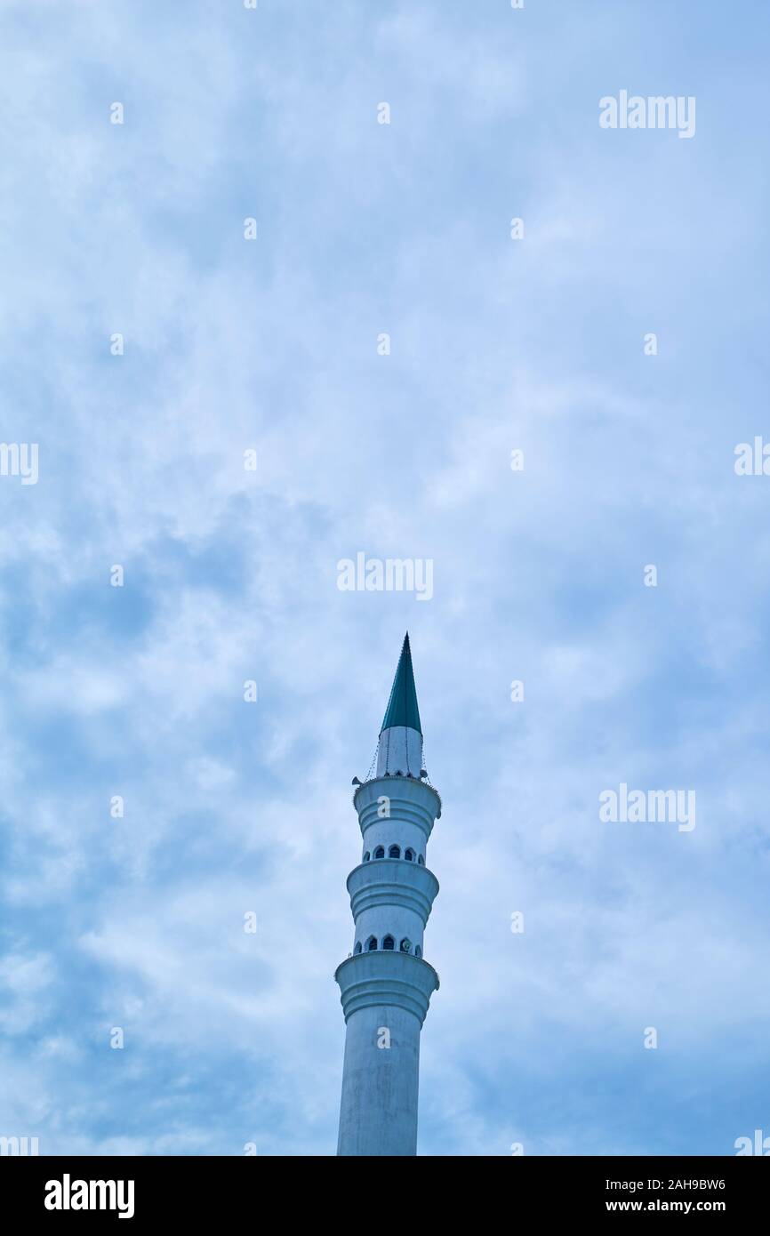 The lone, white minaret of the Al-Kauthar mosque stands against a blue ...