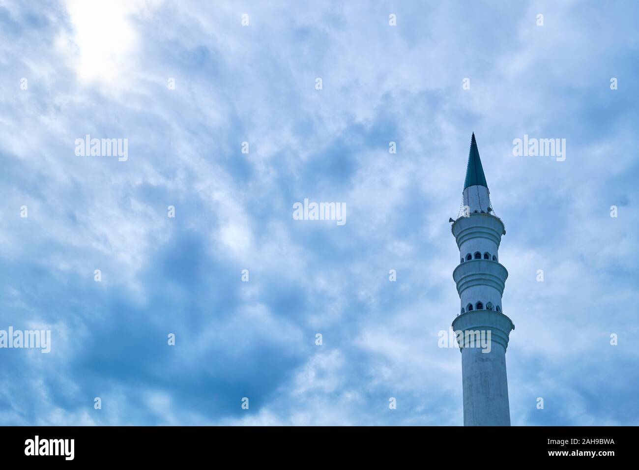 The lone, white minaret of the Al-Kauthar mosque stands against a blue ...