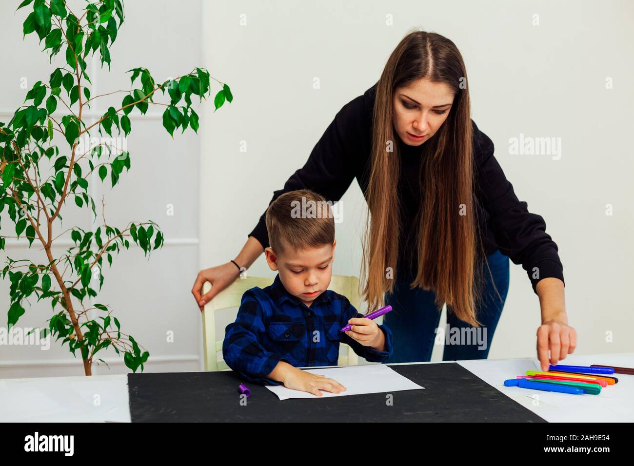 female teacher teaches a little boy to draw at the table Stock Photo ...