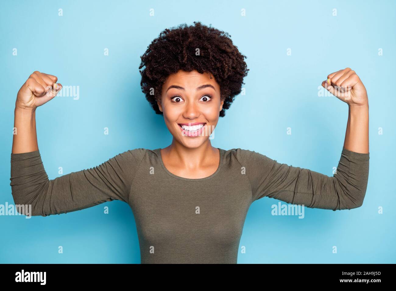 Portrait of amazed crazy mulatto girl show muscles impressed by her ...