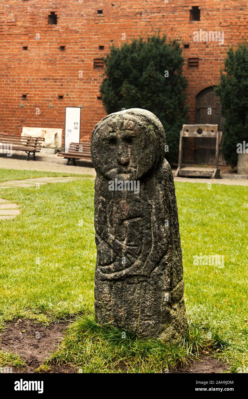 Portrait of Olsztyn Baba, a pagan relic, alone in a green courtyard ...
