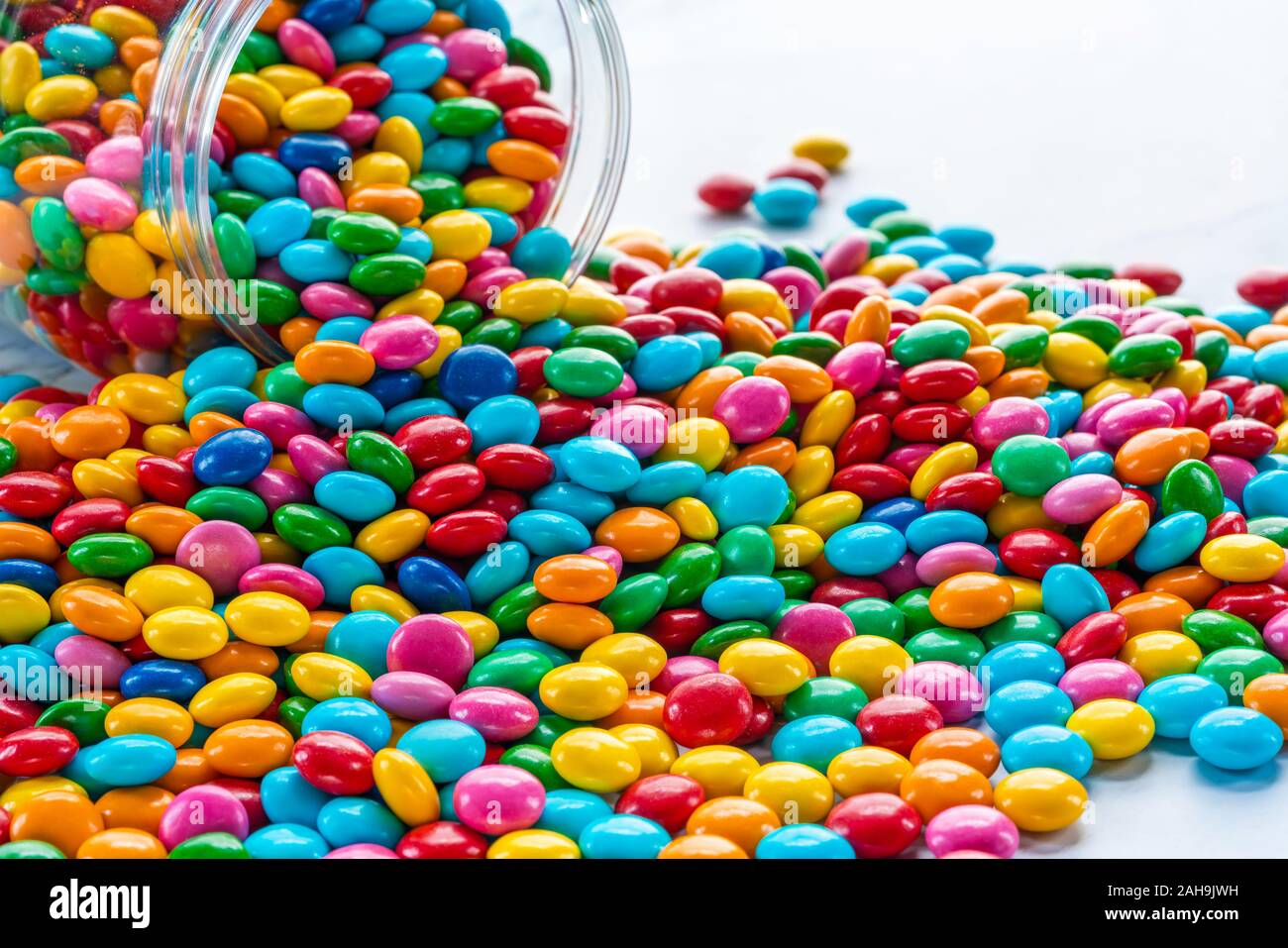Colorful candy spilling out of a jar onto white background Stock Photo ...