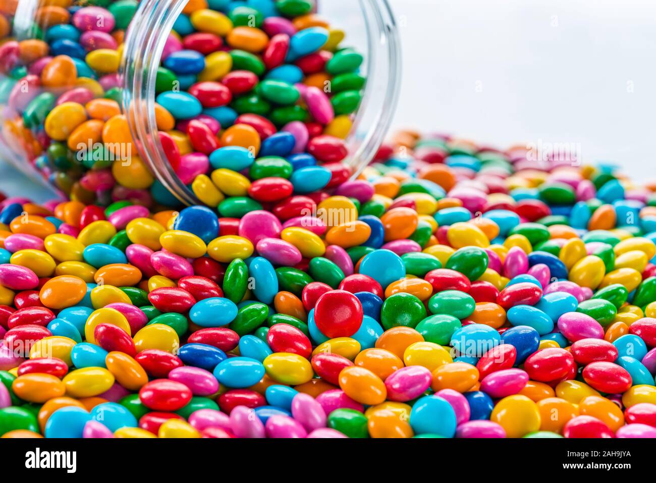 Colorful candy spilling out of a jar onto white background Stock Photo ...