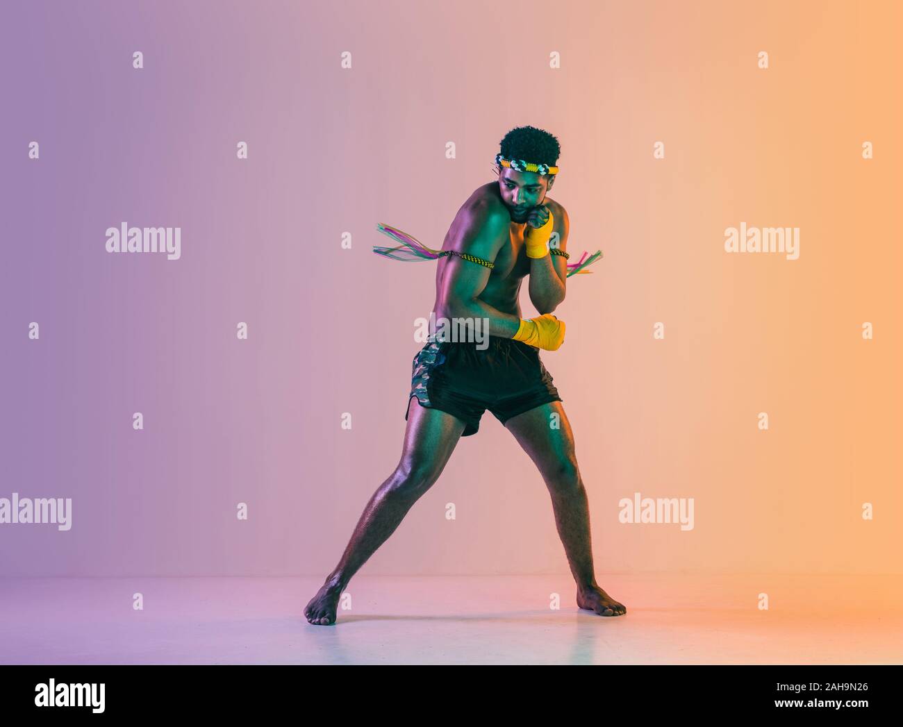 Muay thai. Young man exercising thai boxing on gradient background in ...