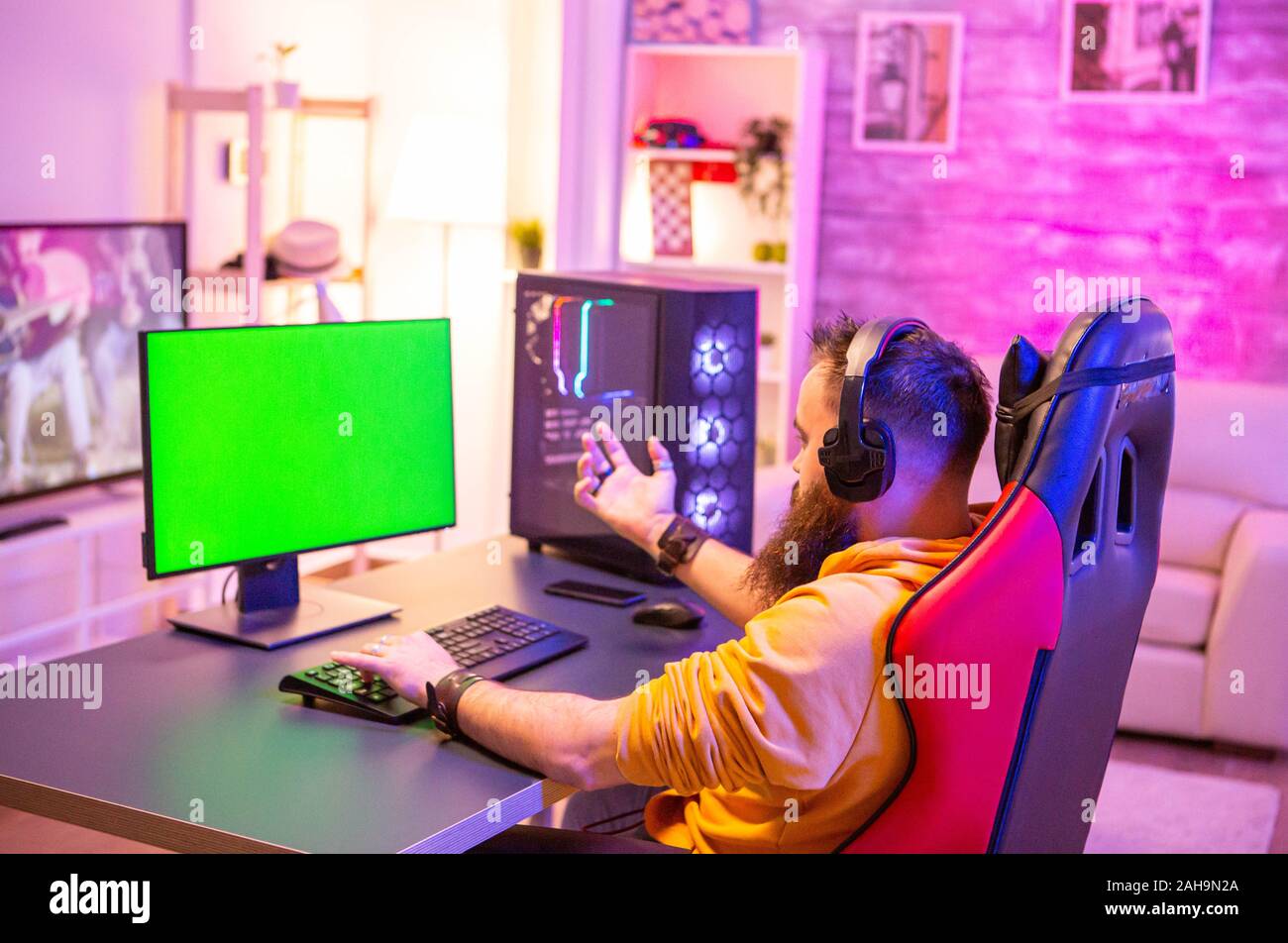 Man playing on powerfull gaming pc in a room with neon lights on a ...