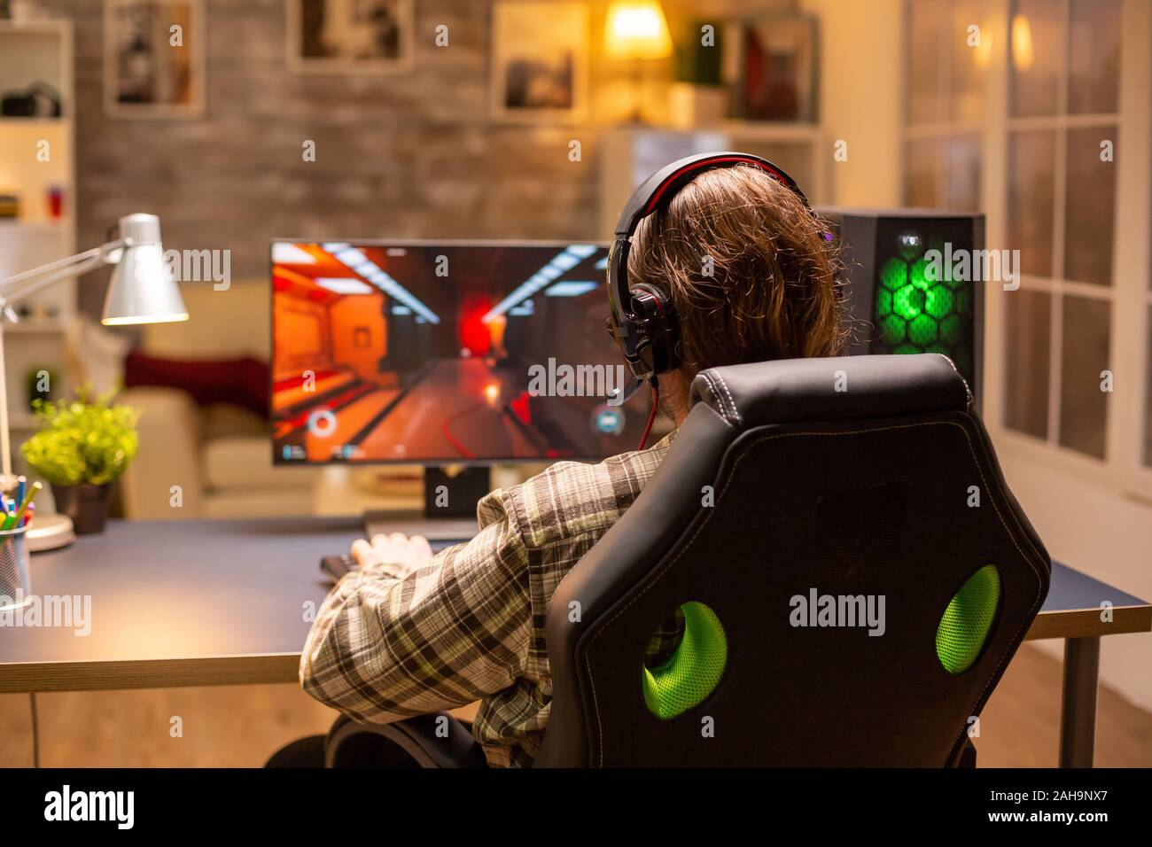 Back view of gamer male playing a shooter on his powerful PC computer ...