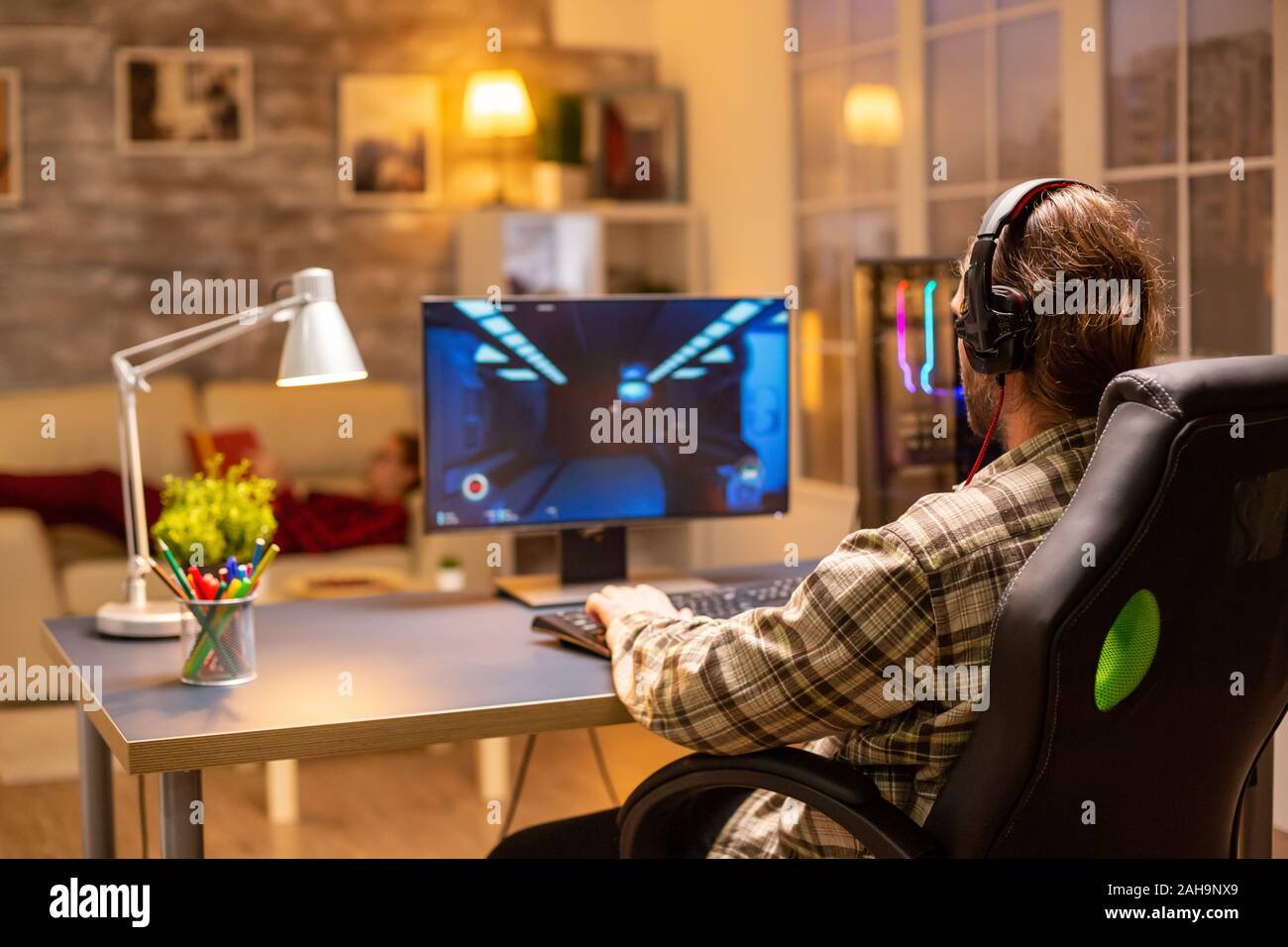 Back view of gamer male playing a shooter on his powerful PC computer ...