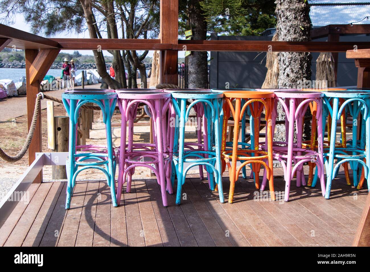 row of colorful stools on timber platform at cafe Stock Photo - Alamy