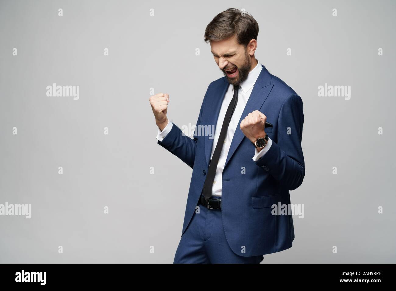 Very happy successful winner gesturing businessman over grey background ...