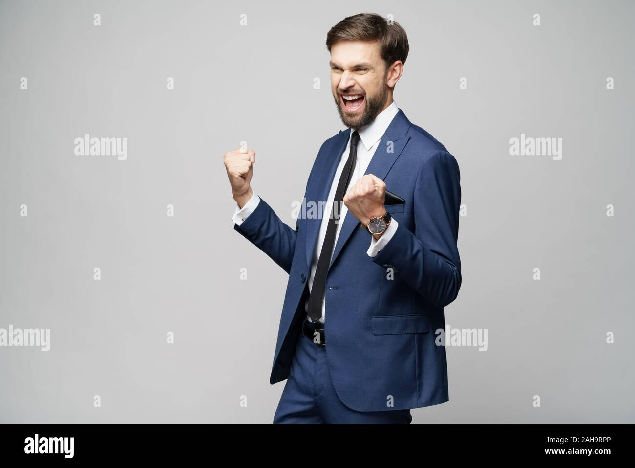 Very happy successful winner gesturing businessman over grey background ...