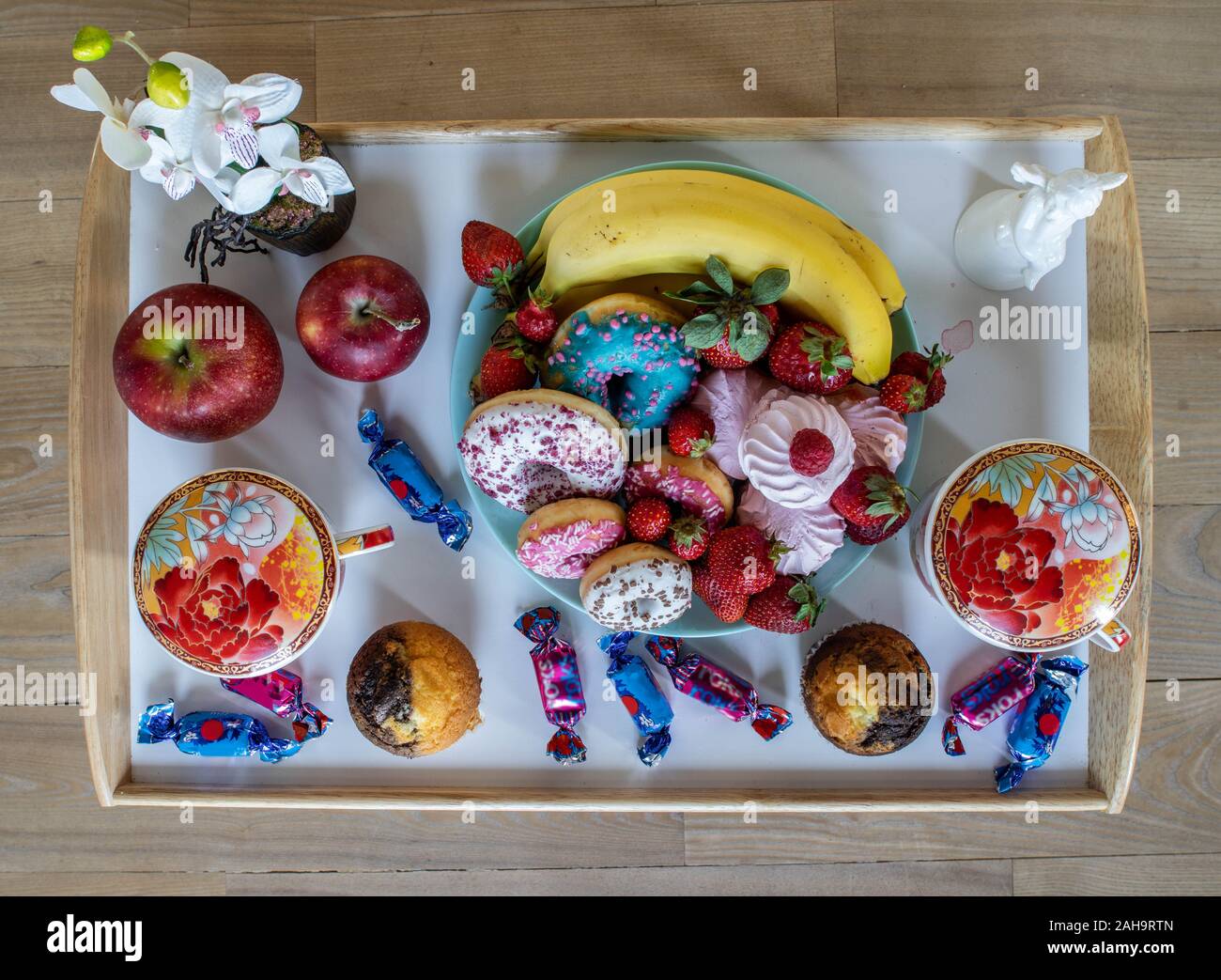 Romantic composition. Two closed cups, two muffins, sweets, donuts and ...