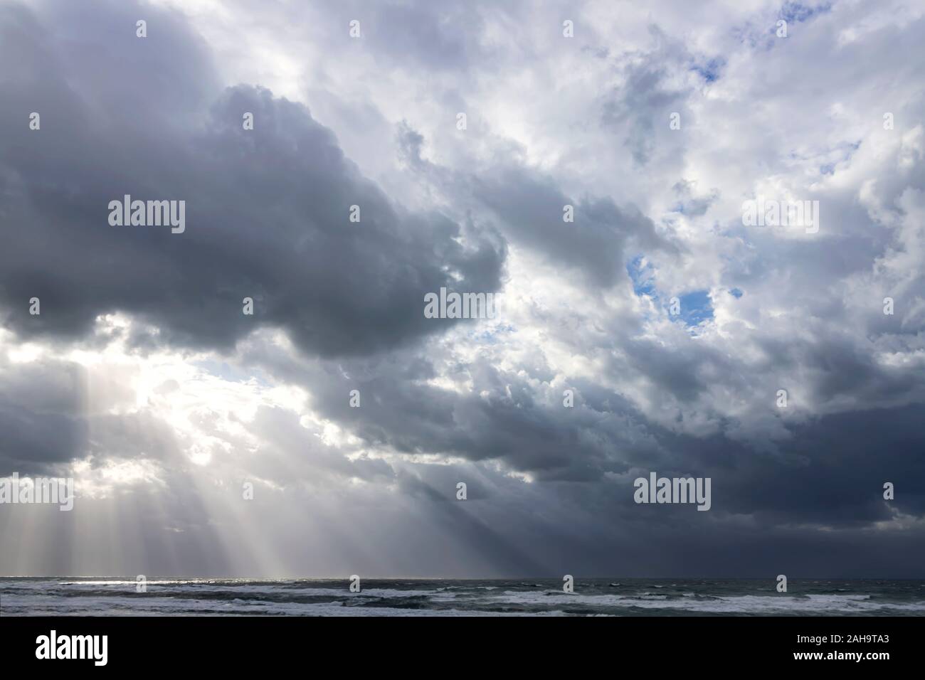 Sun rays breaking through the clouds of a dramatic stormy sky over the ...