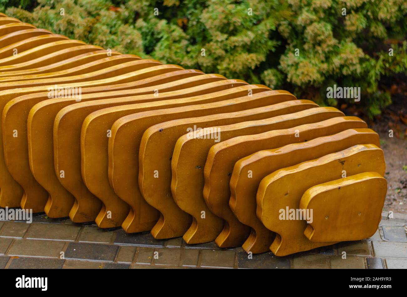 A fragment of a wooden futuristic bench in a city park. Close-up of ...