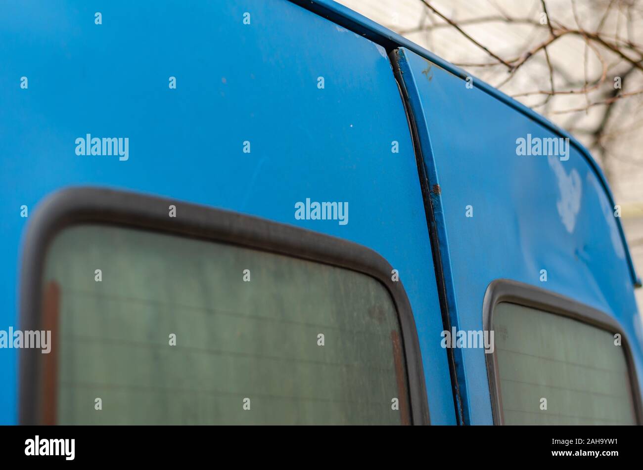 Damaged back door of a minibus. Unclosed door of a tall blue minibus. A ...