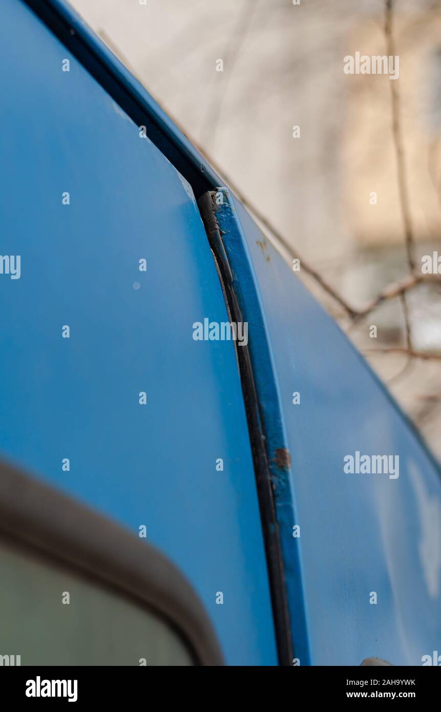 Damaged back door of a minibus. Unclosed door of a tall blue minibus. A ...