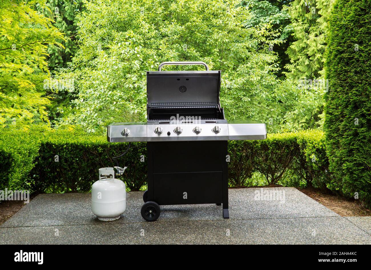large barbeque cooker, with lid up, on concrete outdoor patio with ...