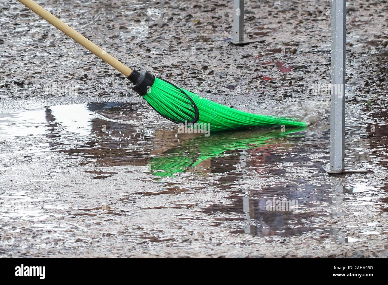 Sweeping puddle of water with green broom Stock Photo - Alamy