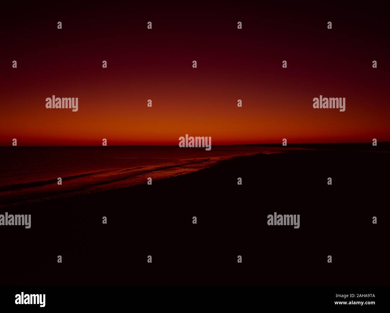 Scary red and orange horizon with the ground and waves in silhouette ...