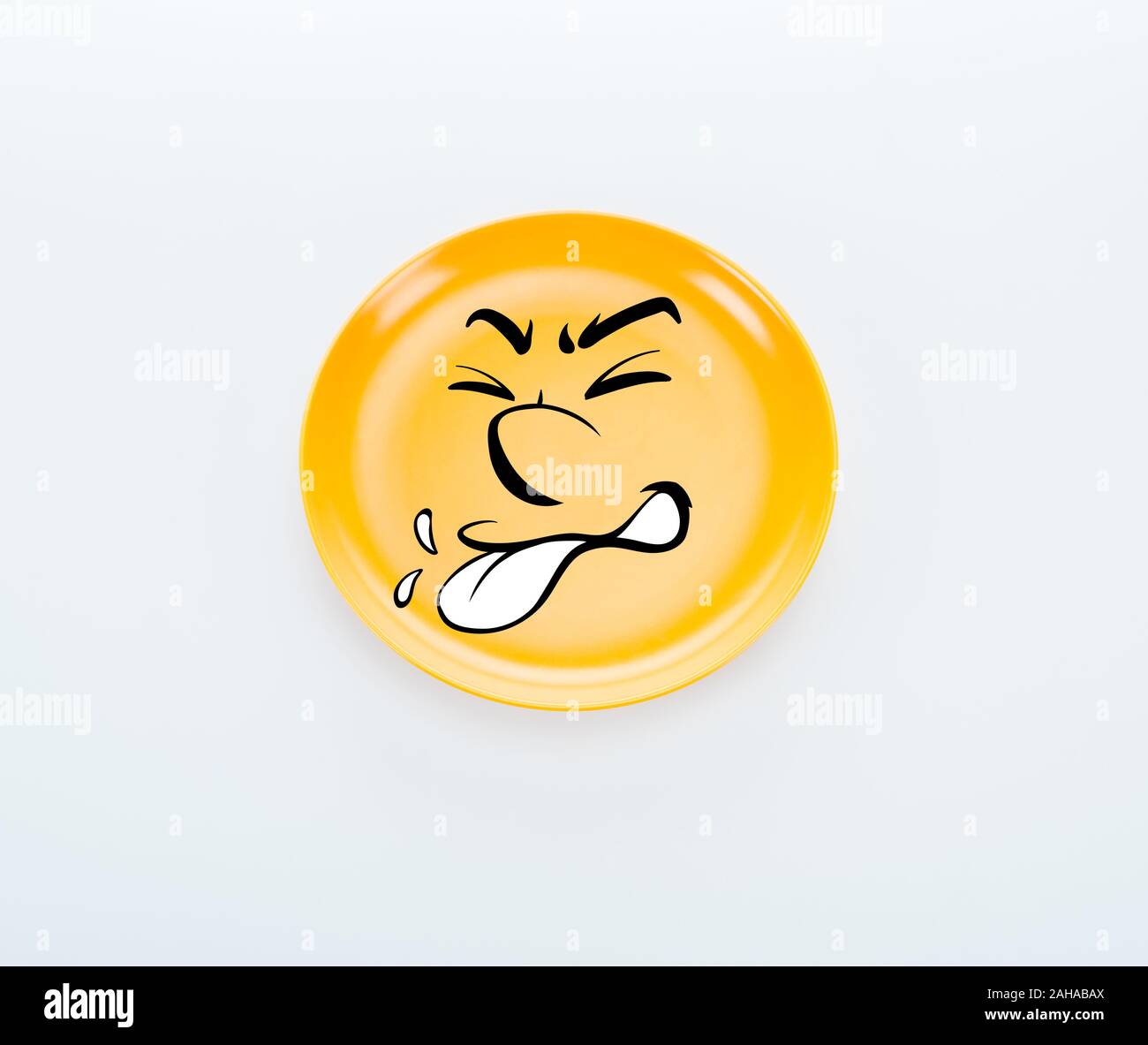 top view of shiny yellow plate with disgusted smiley on white ...