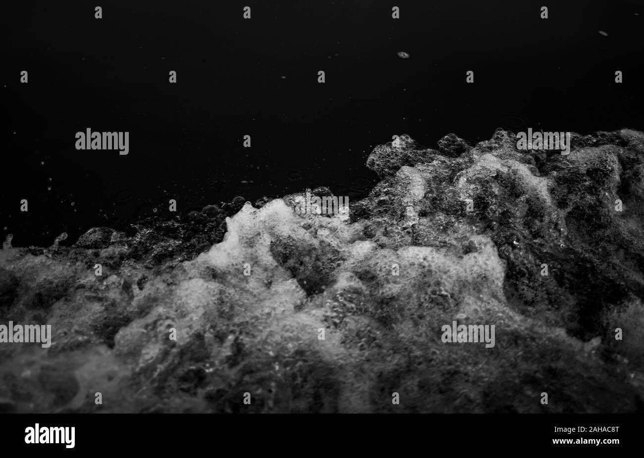 Foaming water with an otherwise calm, dark surface Stock Photo - Alamy
