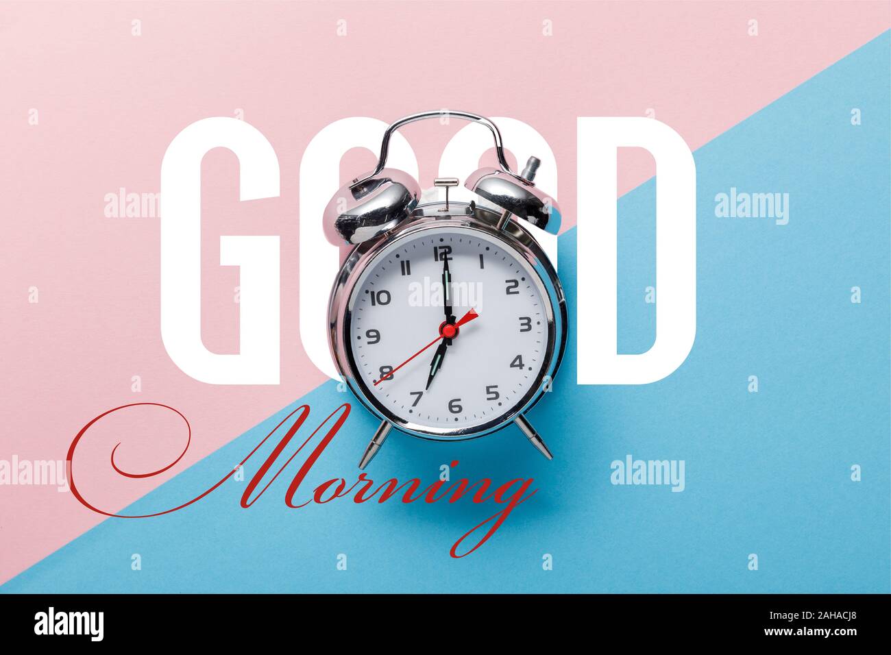 top view of classic silver alarm clock on pink and blue background with ...