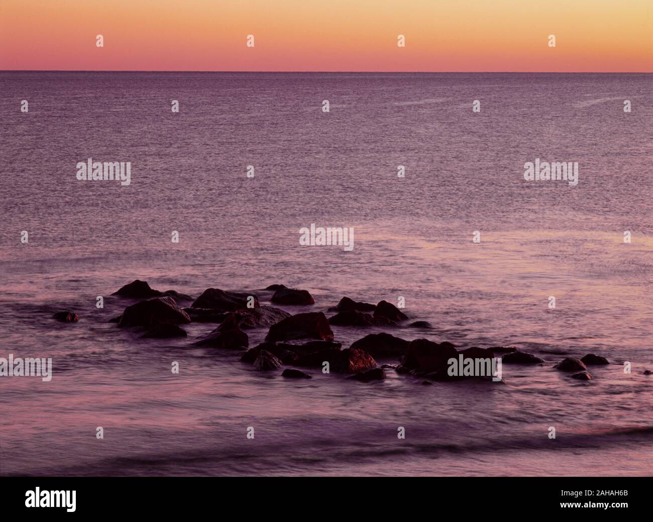 A short rock formation in the ocean at dawn with a colorful sky Stock ...