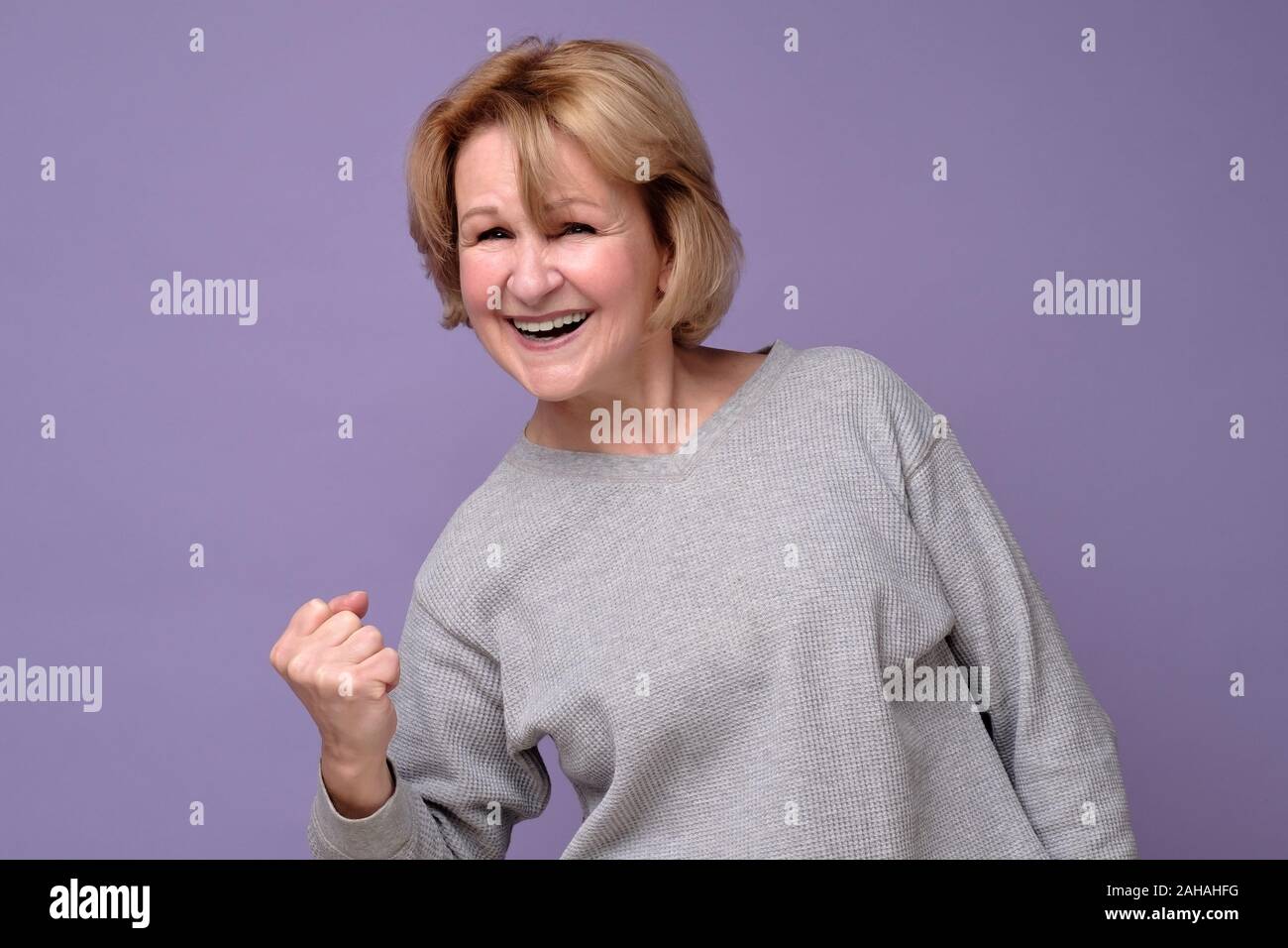 Senior caucasian female winner raising arm , clenching fist ...