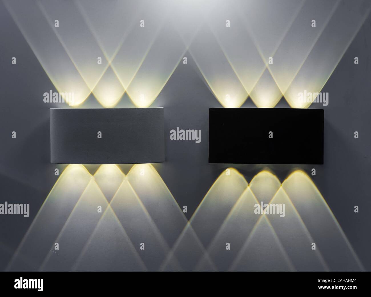 Two wall lights with symmetrical highlights on the wall Stock Photo - Alamy