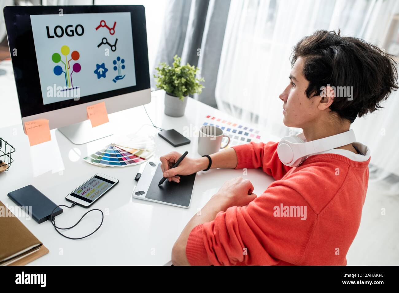 Young serious man concentrating on making logo while looking at ...