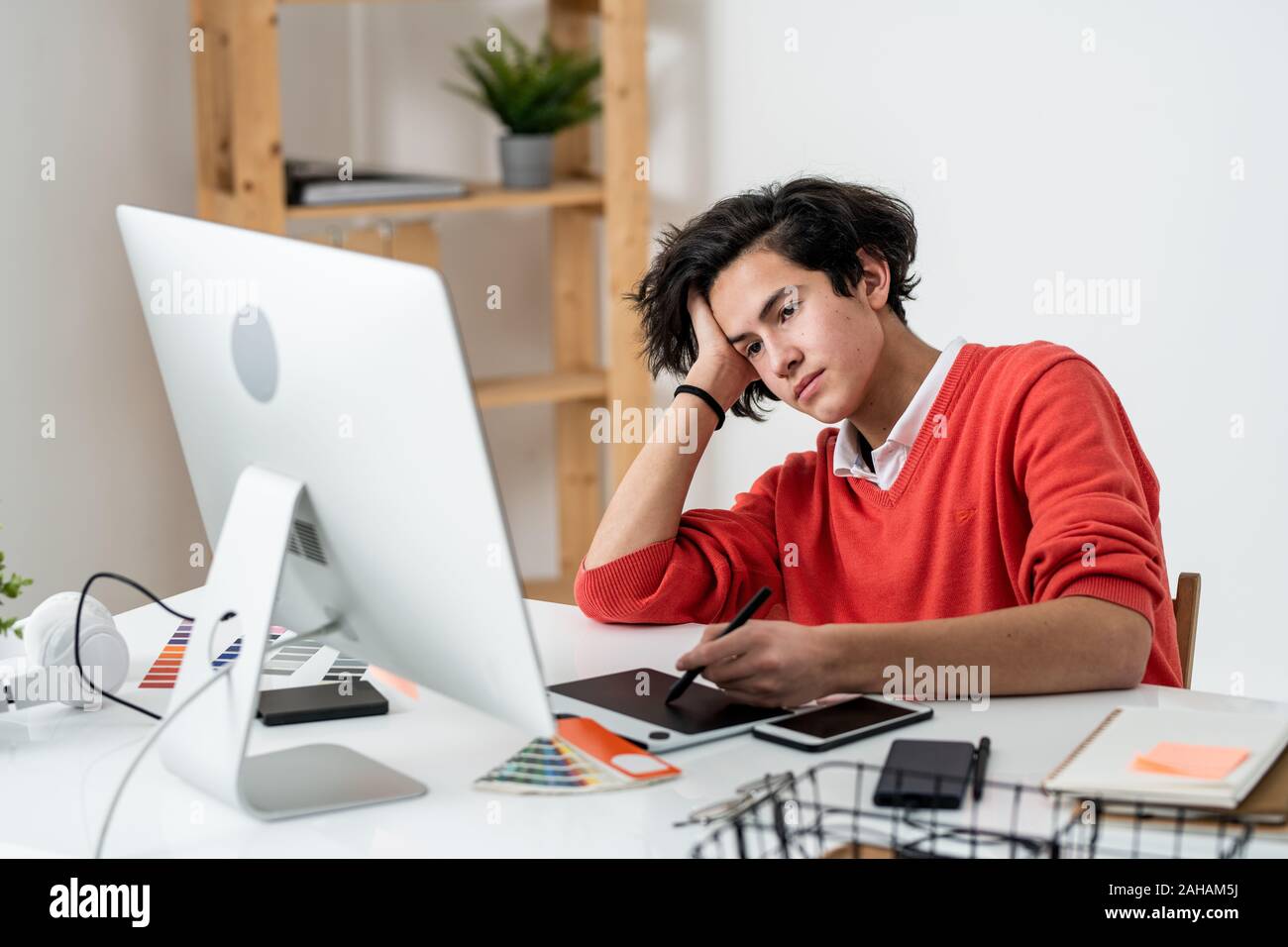 Tired male freelancer looking at computer screen while retouching ...