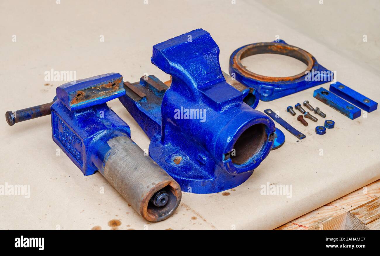 Parts of disassembled metal vise on the table in the workshop. Heavy ...