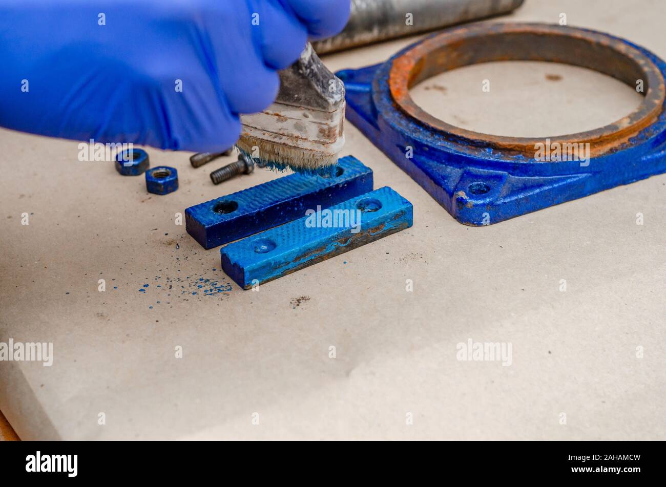 Worker paints a metal vise with blue paint. Stripping old paint Stock ...