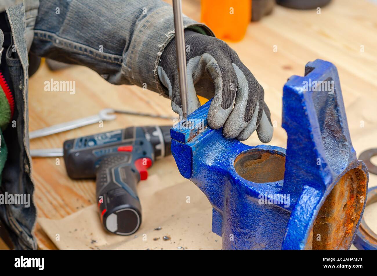Worker man dismantles old metal vice in workshop Stock Photo - Alamy
