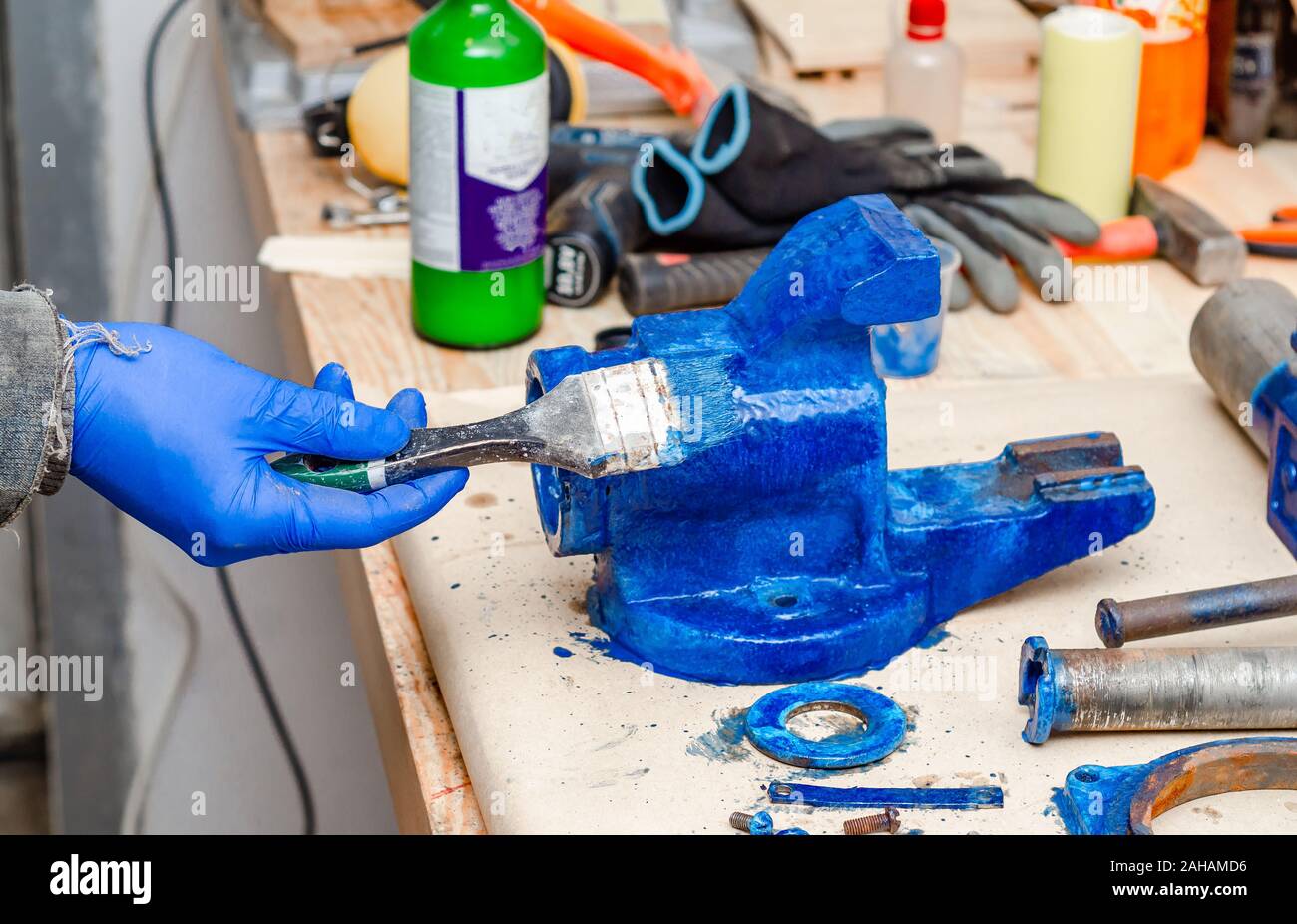 Worker paints a metal vise with blue paint. Stripping old paint Stock ...