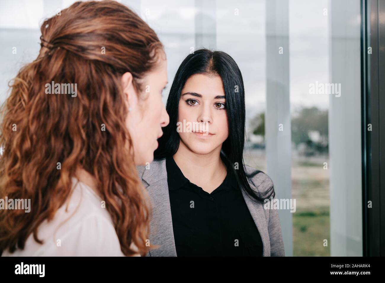 Two business women talking near a window in the office Stock Photo - Alamy