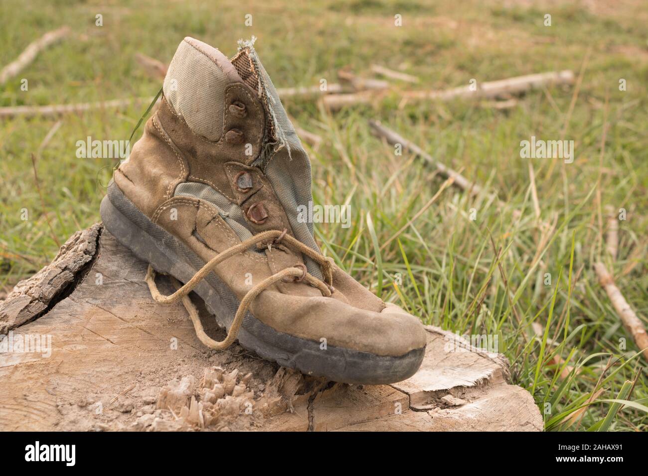 An old dirty boot on a dark background is lighted up by a sunlight ...