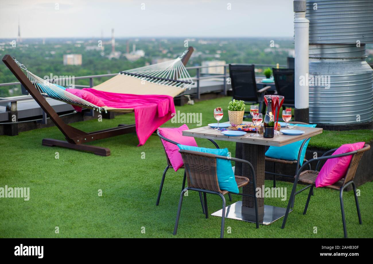 View of the city from rooftop terrace. Relax zone with hammock and ...