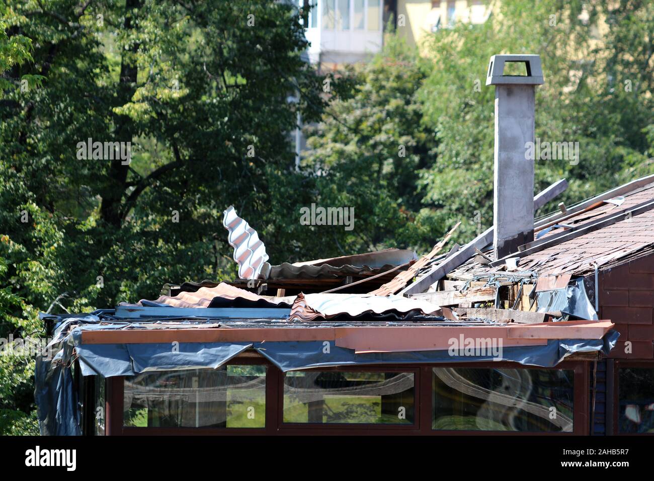 Concrete chimney next to destroyed cracked roof on top of closed front ...